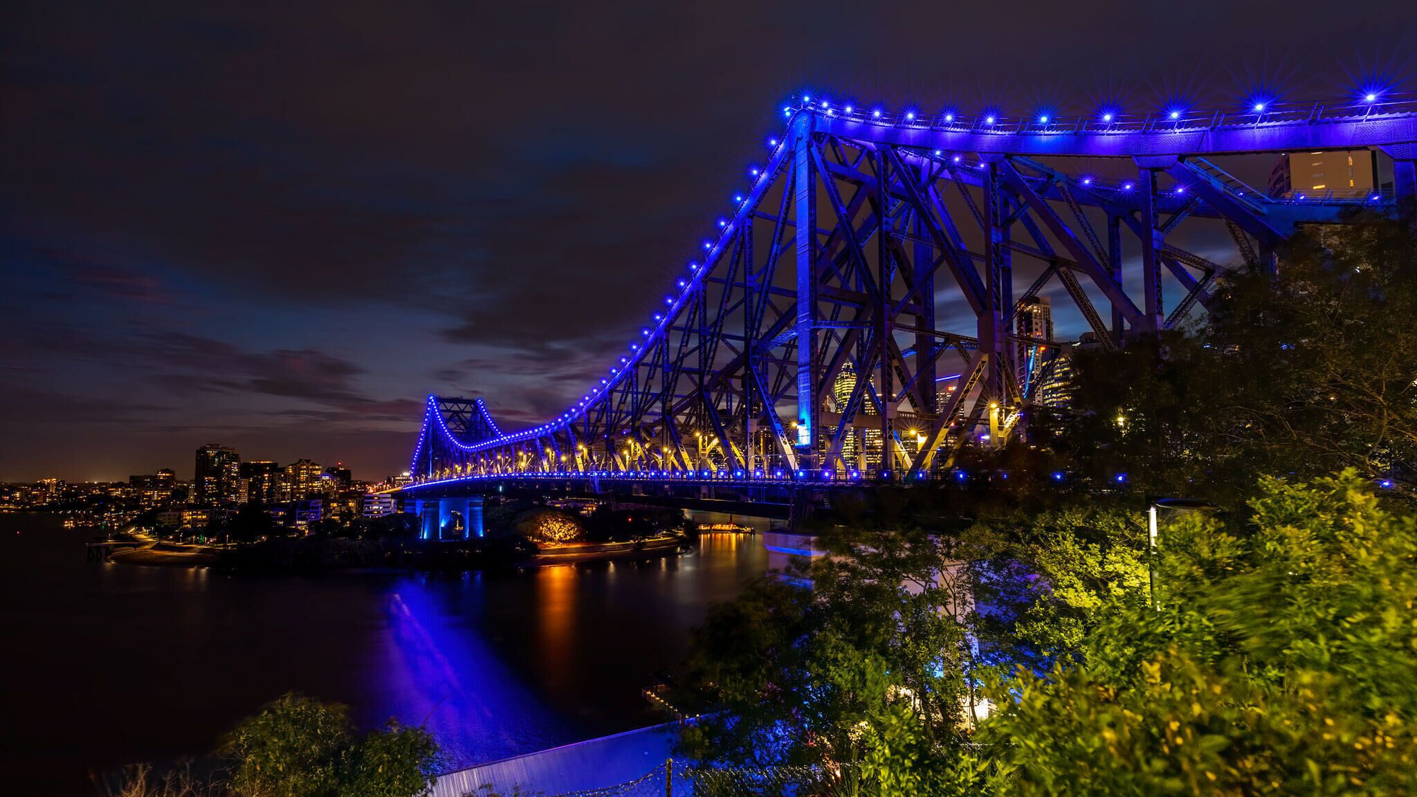 Uma ponte bem iluminada com luzes azuis à noite.