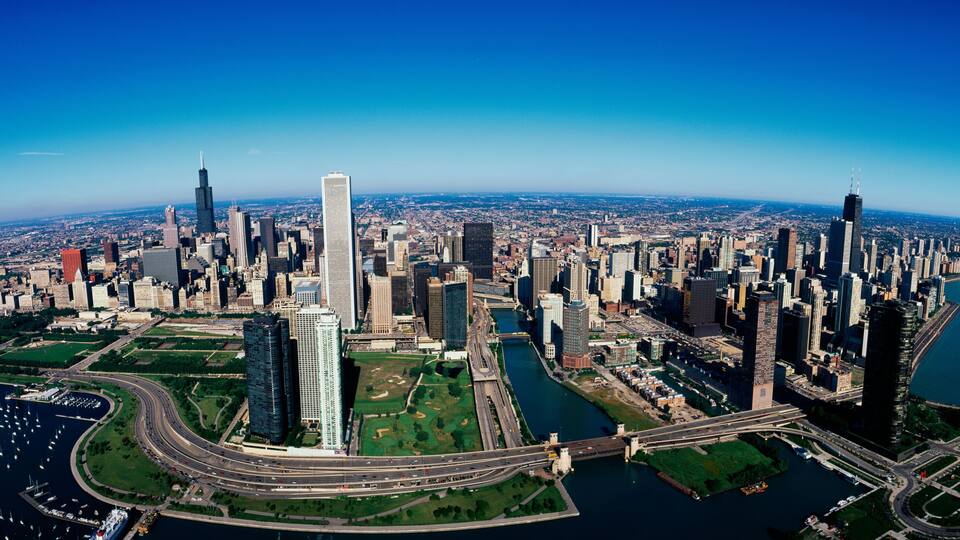 Vista panorâmica de um horizonte urbano com arranha-céus imponentes, um rio e uma ponte.