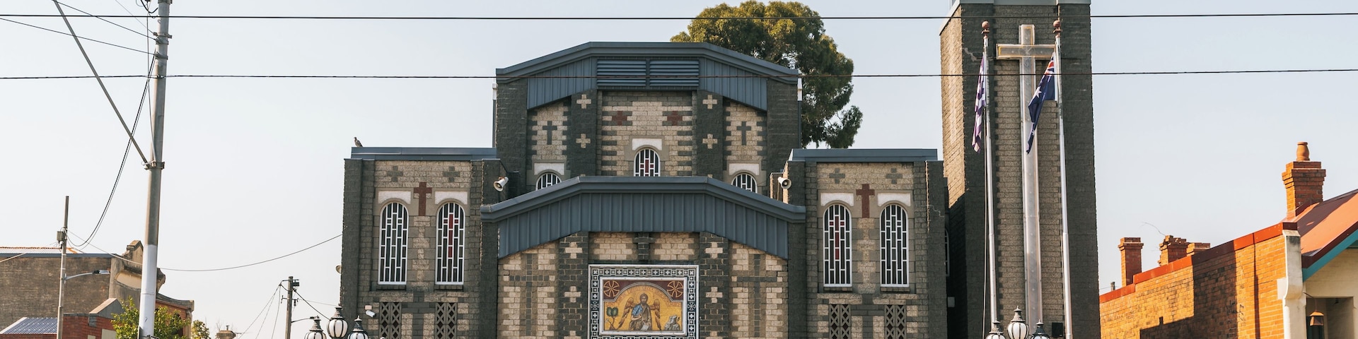 Uma igreja histórica com uma torre de sino, fachada detalhada e uma grande cruz.