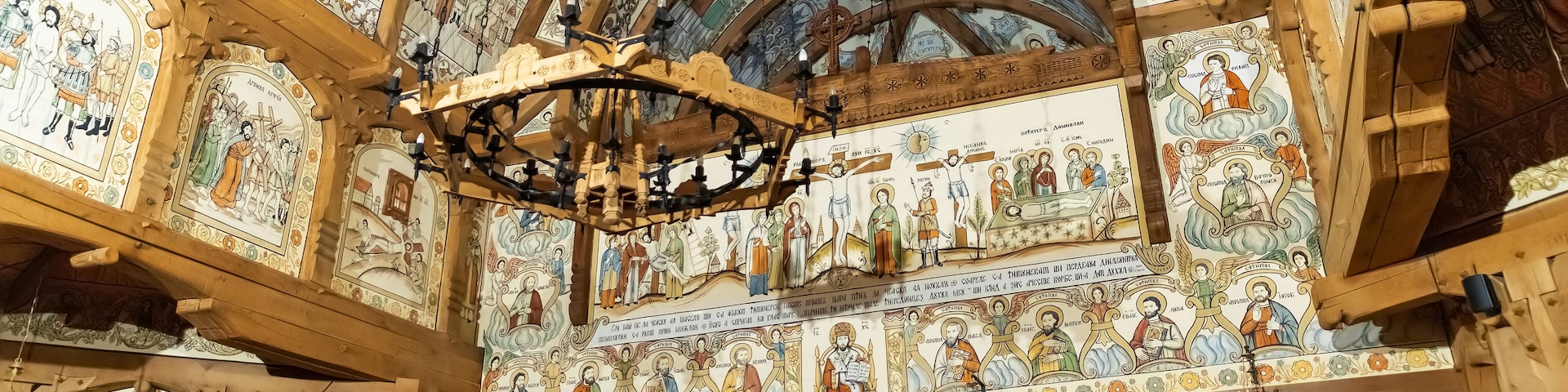Interior ricamente decorado com afrescos detalhados, vigas de madeira e ícones religiosos.