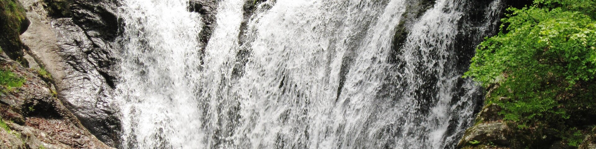 Uma cascata com vários níveis, rodeada por vegetação exuberante.