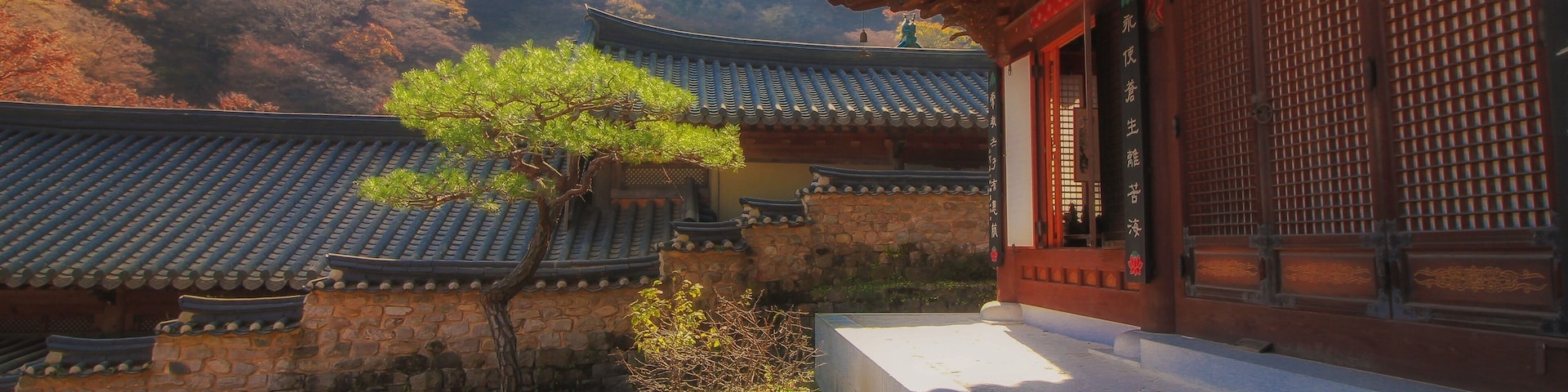 Um templo coreano tradicional com paredes de pedra, telhados cobertos de telhas e uma escadaria de pedra que leva à entrada.