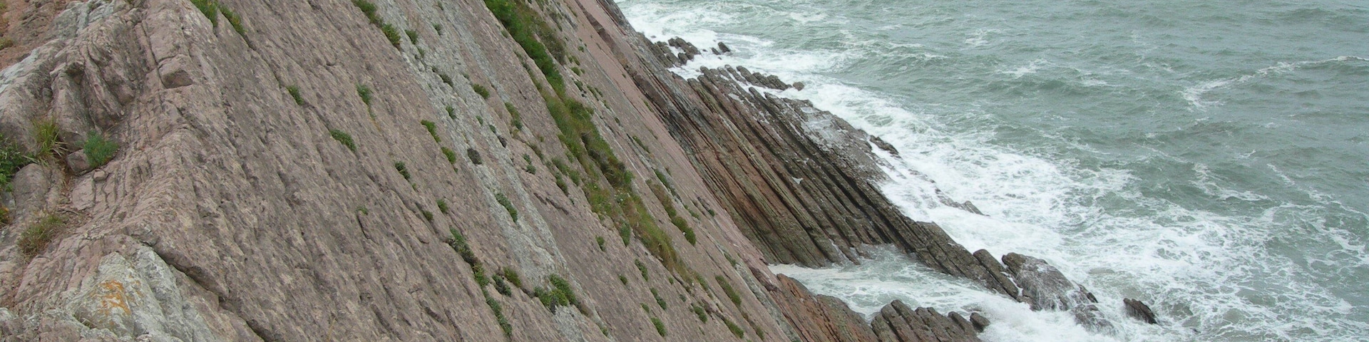 Um litoral rochoso com ondas quebrando na praia.