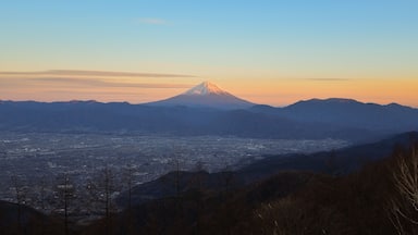 Uma montanha com pico nevado, um vale com uma cidade e montanhas ao longe.