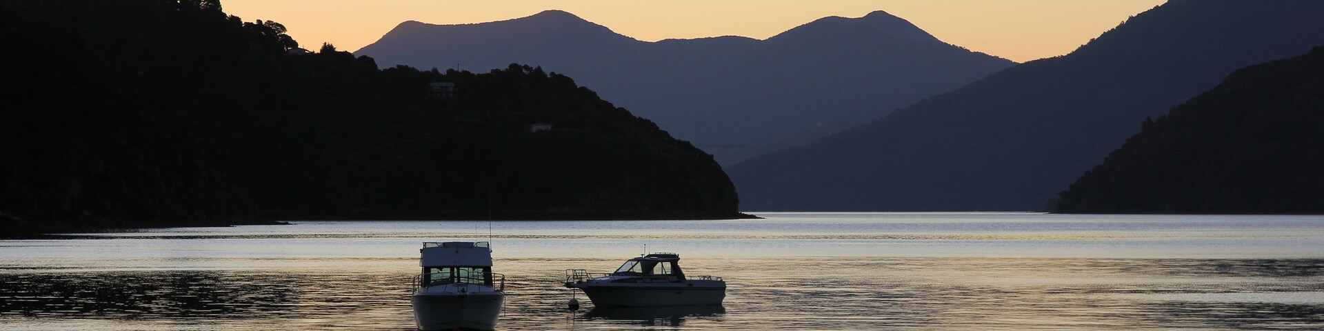 Um barco em águas calmas, com montanhas ao fundo.