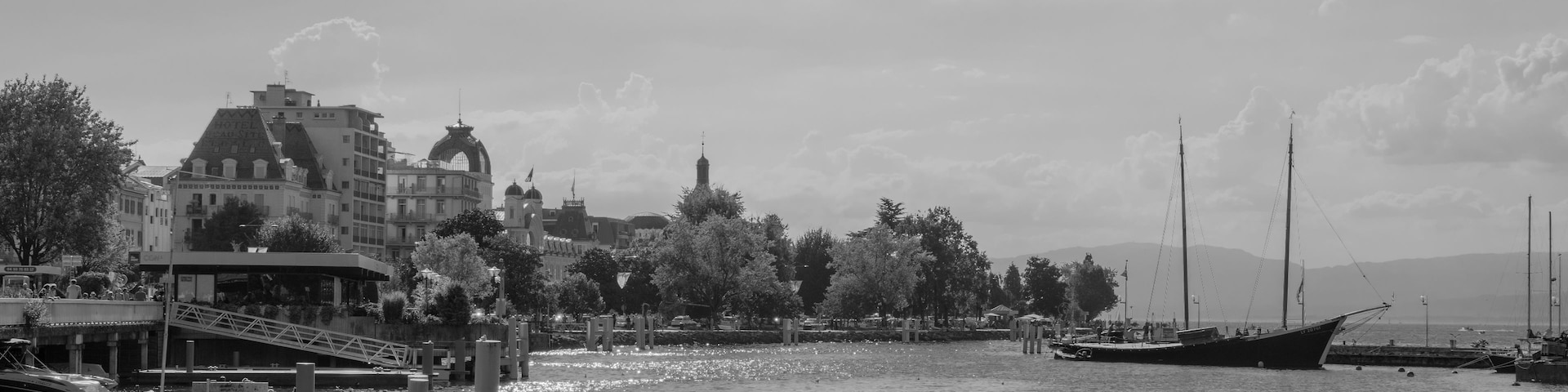 Uma orla com barcos, uma ponte e edifícios, incluindo um hotel.