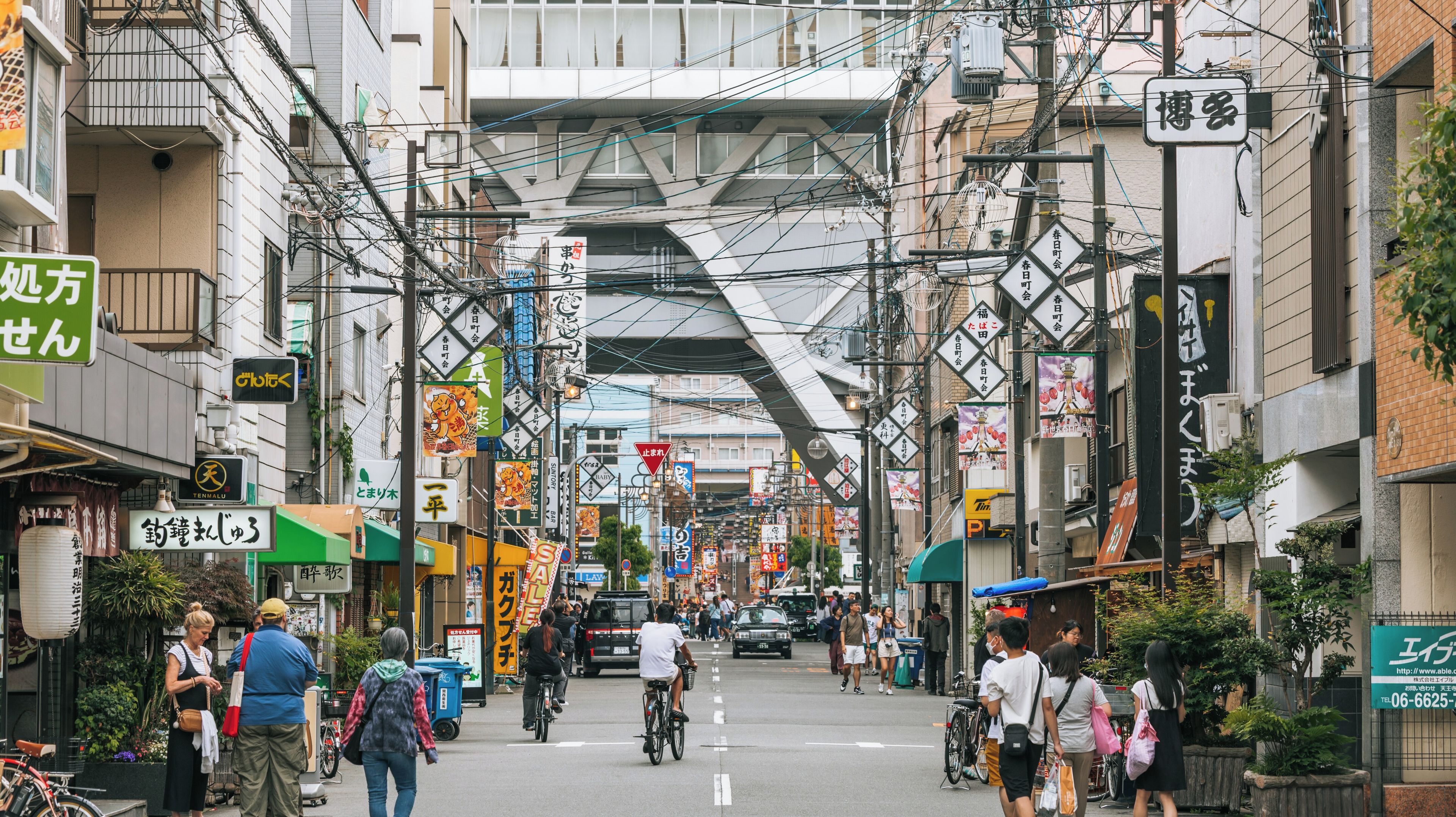 Uma rua urbana movimentada com pedestres, ciclistas e veículos.