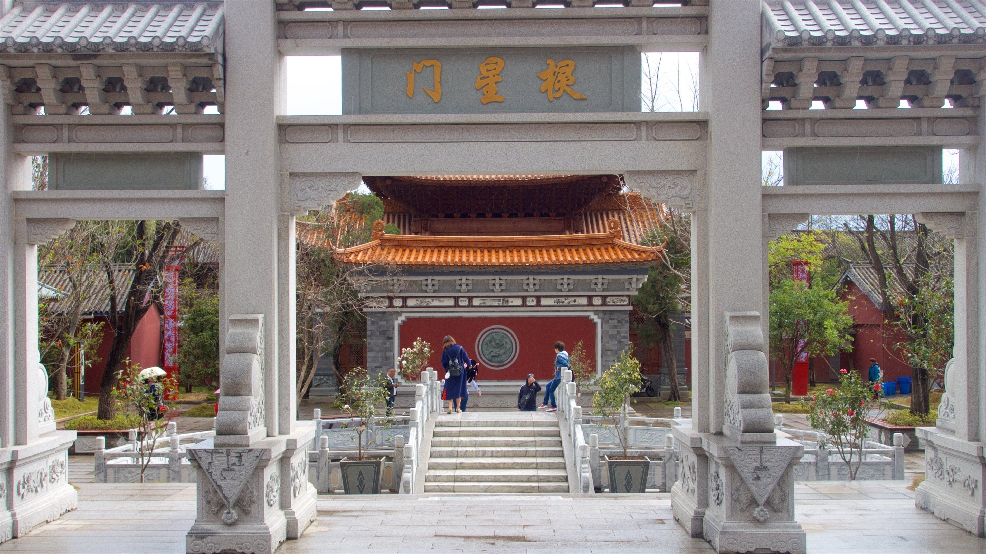 Um portão tradicional chinês com esculturas elaboradas e telhado vermelho.