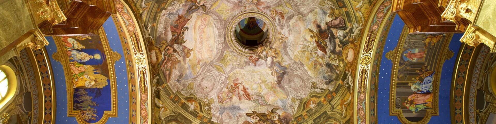 Teto ricamente decorado, com frescos detalhados e detalhes dourados.