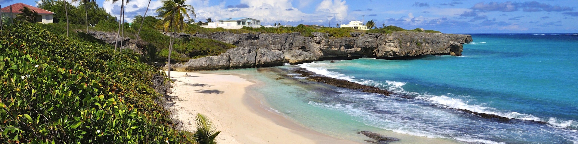 Uma praia tropical com águas turquesa cristalinas, areia dourada e vegetação exuberante.