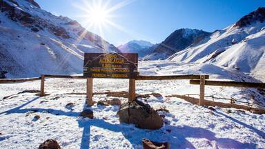 Placa em área montanhosa nevada, com o sol brilhando intensamente.