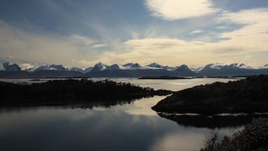 Um lago calmo rodeado por montanhas e um céu claro.