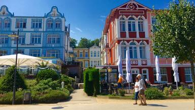 Rua com edifícios coloridos, mesas ao ar livre e um céu azul límpido.