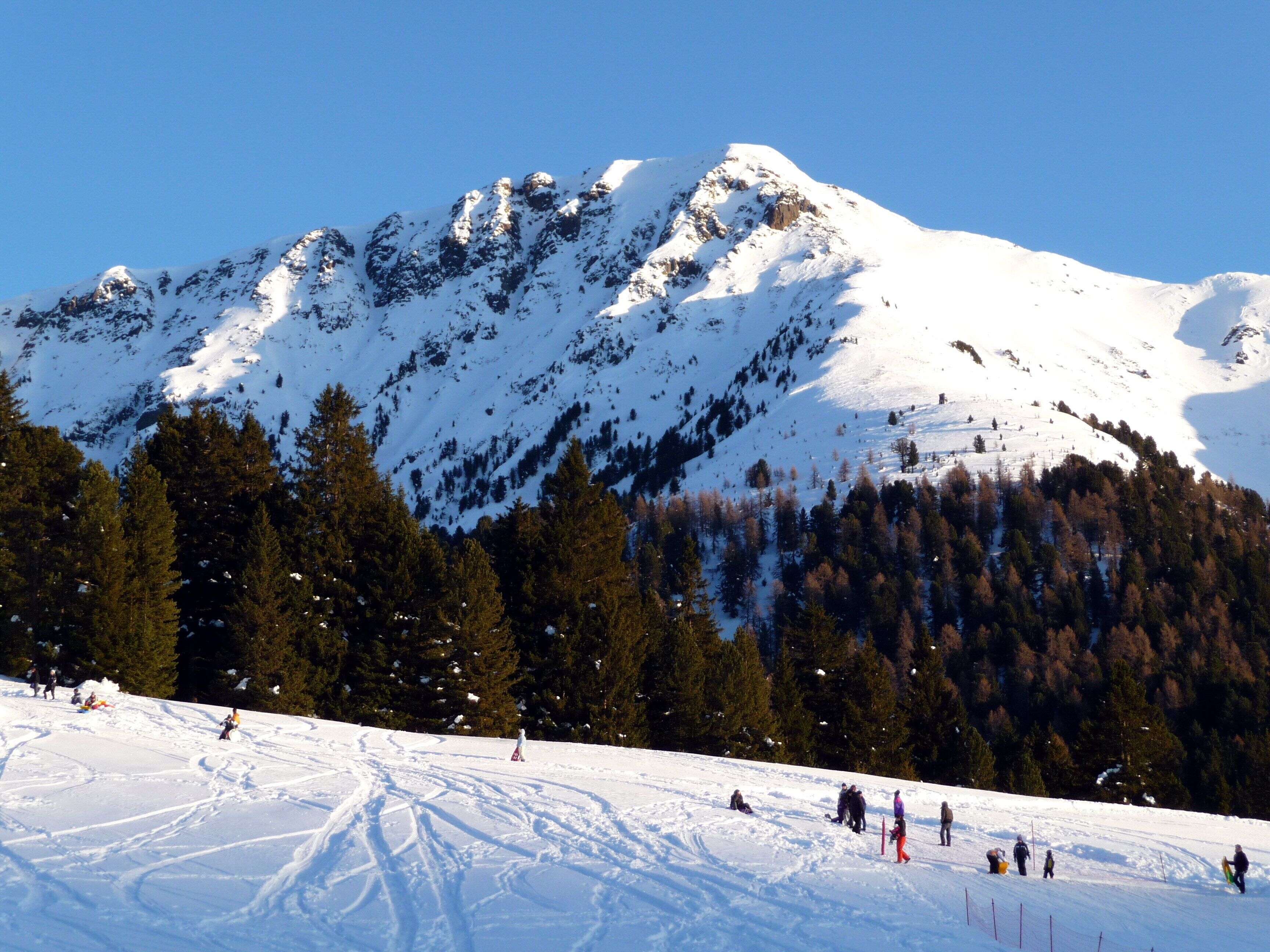 Montanha coberta de neve com esquiadores e snowboarders.