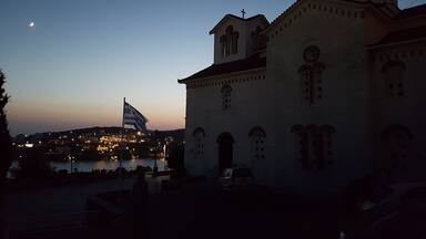 Uma igreja com uma cruz no topo, uma bandeira e uma lua crescente no céu.