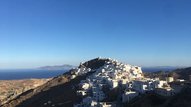 Uma vila costeira com edifícios brancos numa encosta, com vista para o mar.