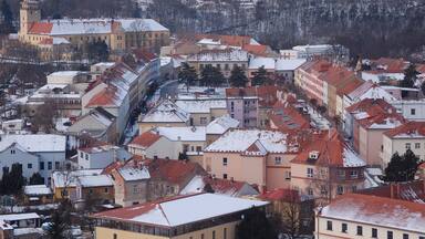 Uma cidade coberta de neve com edifícios históricos e uma torre imponente.