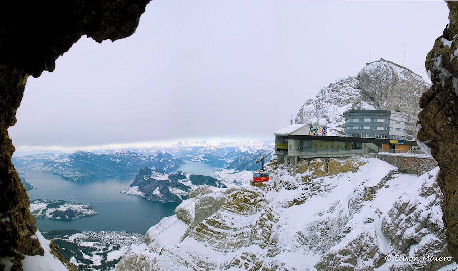 Montanha coberta de neve com um teleférico e um edifício com a inscrição