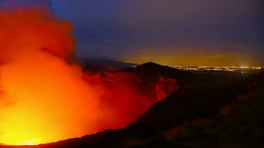 Uma cratera vulcânica com lava incandescente à noite.