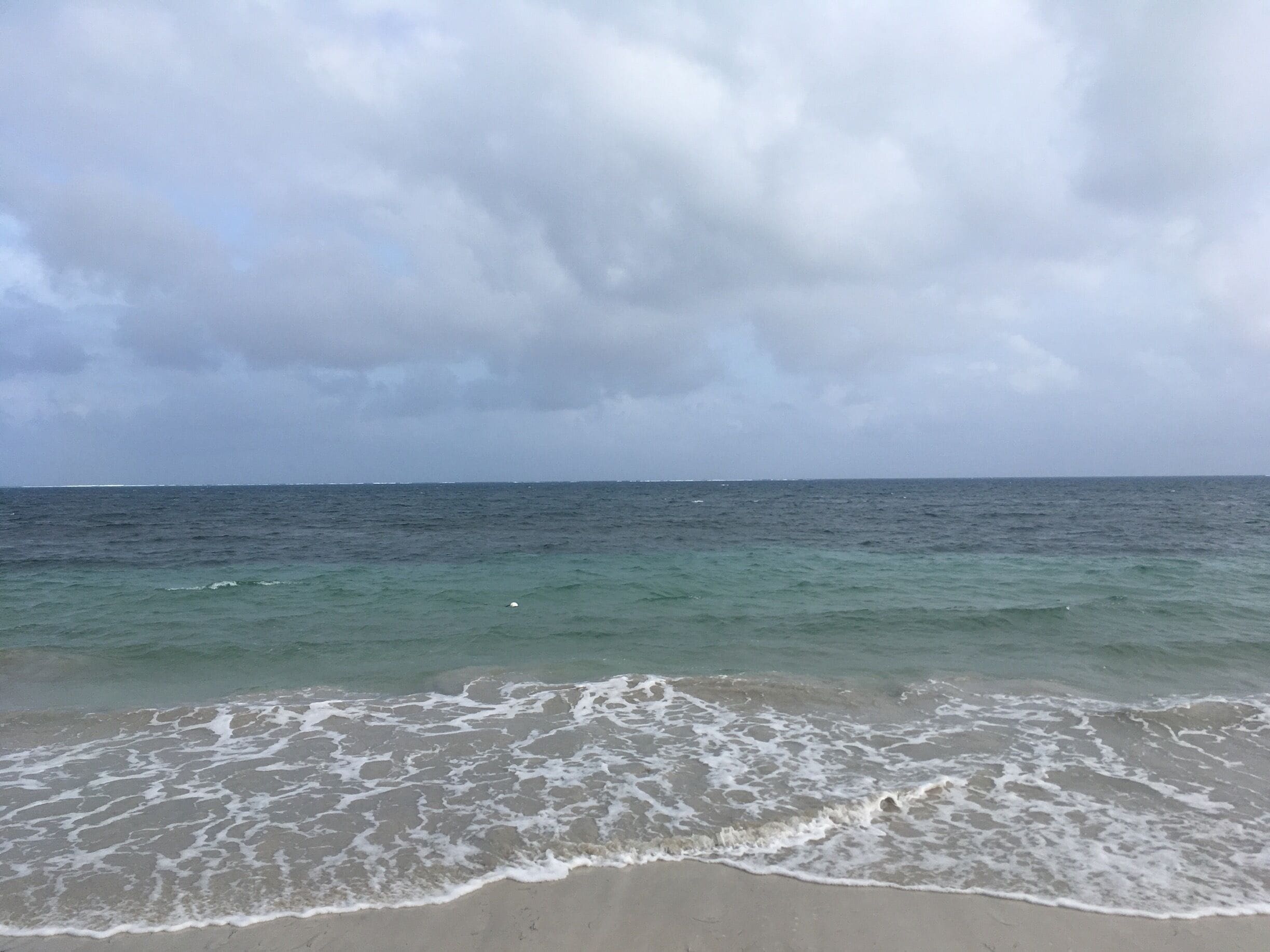 Uma praia com ondas quebrando na costa sob um céu nublado.