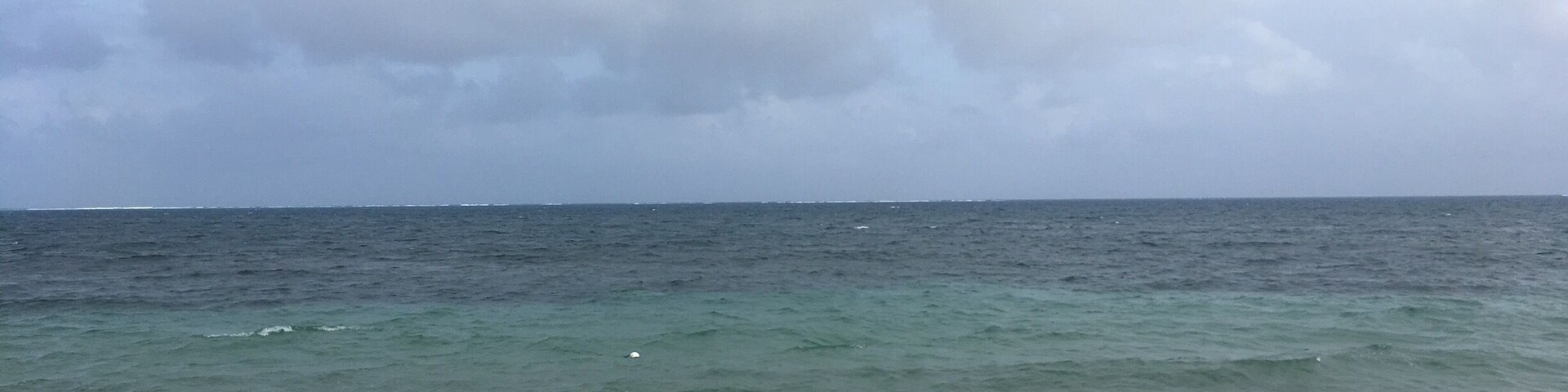 Uma praia com ondas quebrando na costa sob um céu nublado.