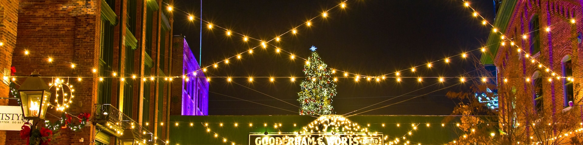 Uma rua festiva com luzes de Natal, uma árvore de Natal grande e decorações de festas.