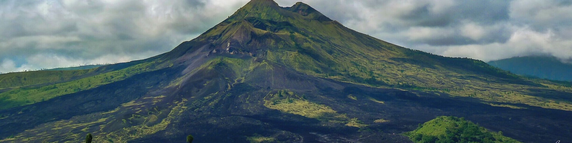 Mount Batur is the easiest climb of the three volcanos and provides spectacular views of Lake Batur and the ocean. It is also Bali’s most active volcano, so check whether it is safe to climb before you go.
Most people do the climb as an organized tour, but you can do it on your own if you prefer. If you decide to do the trek without a guide, be prepared to deal with local guides in Kintamani, the town where the trek starts, who have a reputation for being extremely pushy and doing almost anything to hinder people without a guide to reach the summit.
The track starts out as dirt path, but as it quickly gets steeper it also gets rockier and after a while vegetation is mainly limited to grasses growing among the rocks. Before reaching the summit, a small vender sells refreshments.
On the summit views reach as far as Mount Rinjani, and if you have a guide, he or she might cook you an egg boiled in volcanic steam before the descent.
Hight: 1717 meter
Difficulty: The trek is straight forward, so if you are in decent shape, you shouldn’t have many problems.
Trip length: It takes one to two hours to reach the summit and the same time to get down, but you should also include time to enjoy the views and explore the rim of the crater.