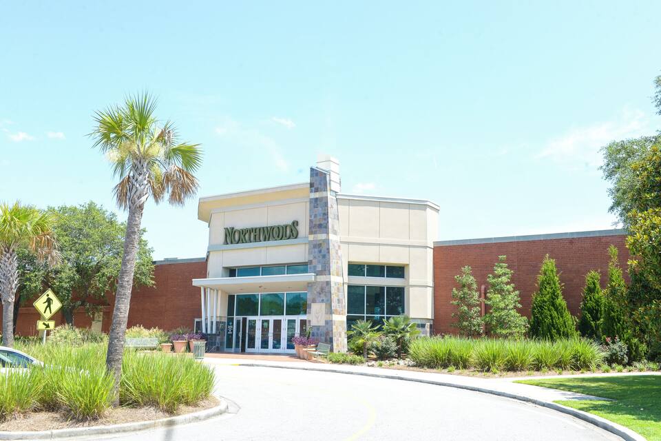 A building with a sign reading "Northwoods" and a pedestrian crossing sign.
