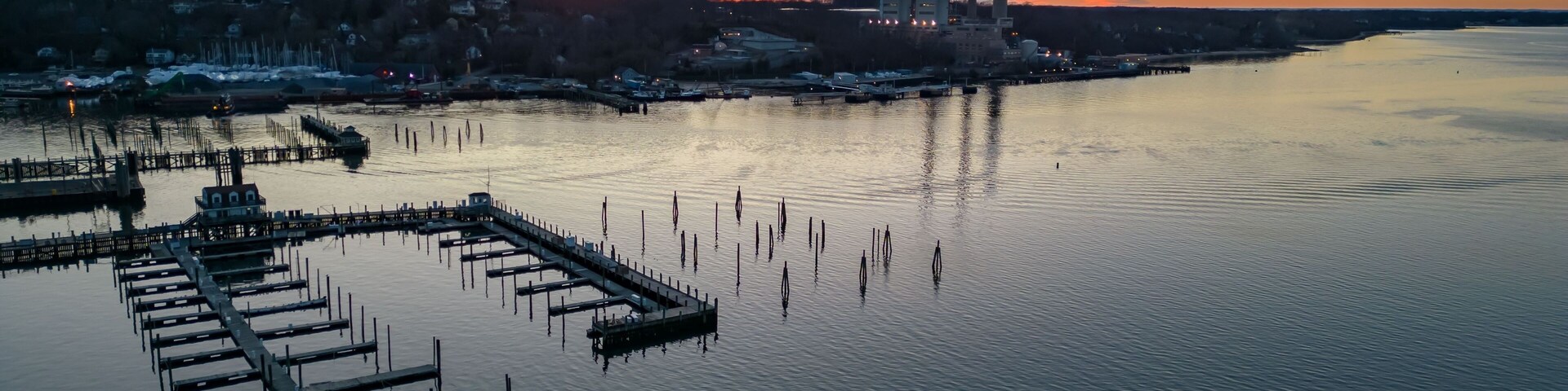 Um pôr do sol sobre um porto calmo, com cais e um navio.