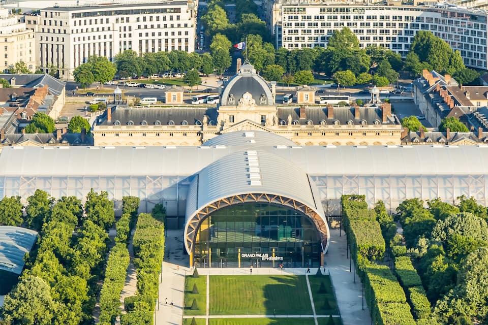 Um edifício grande e moderno com uma cúpula e uma estátua em frente.