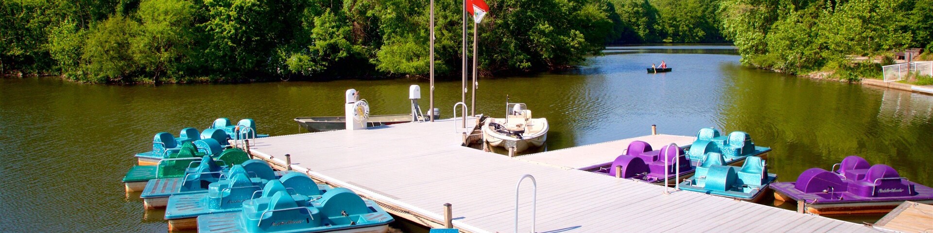 Um cais com barcos a remo e um mastro com a bandeira americana e a bandeira do estado de Maryland.