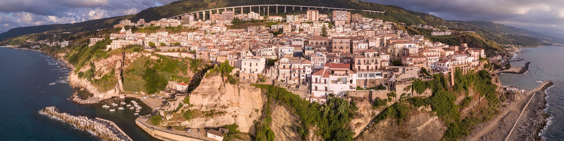 Uma cidade costeira com uma ponte, costa rochosa e edifícios densos.