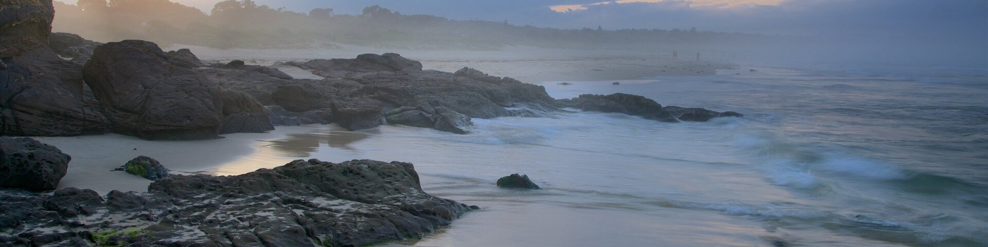 Litoral rochoso com ondas ao pôr do sol.