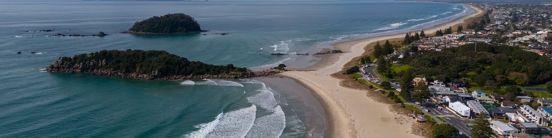 Uma cidade costeira com praia, oceano e uma pequena ilha.