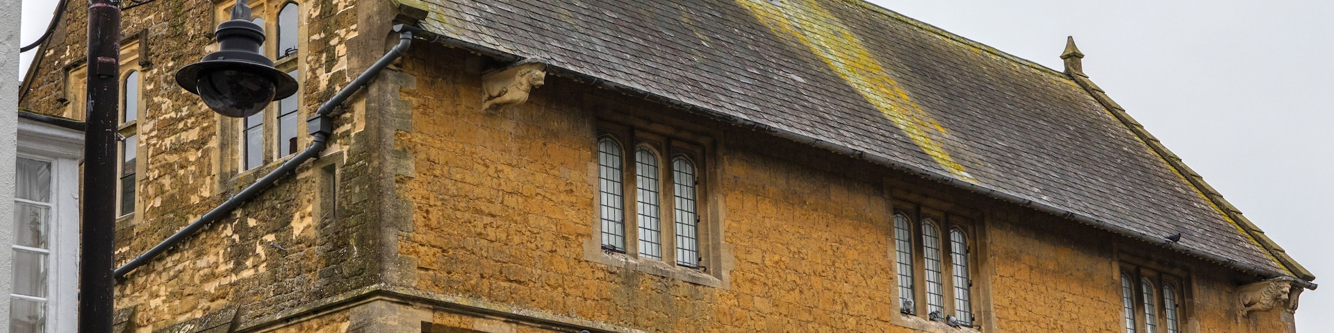 Um edifício histórico com uma torre de relógio, janelas em arco e um indicador de vento.