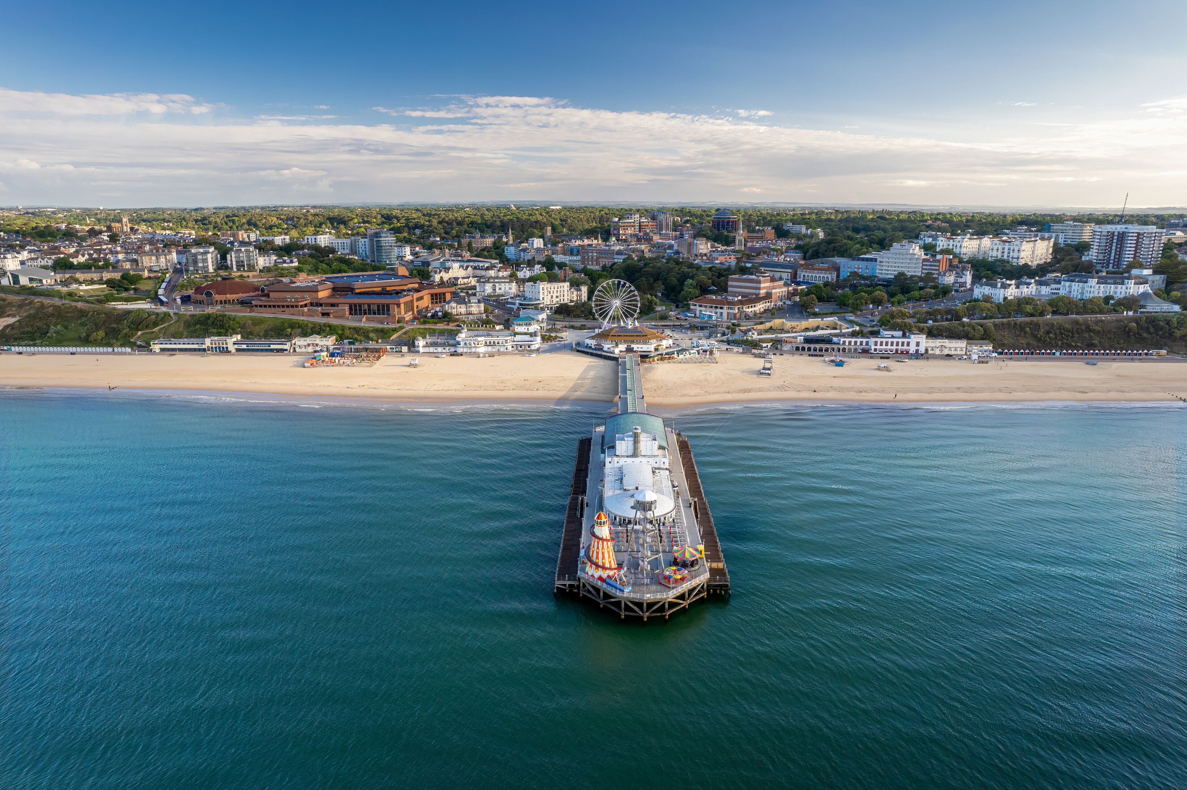 Um grande navio atracado em um cais, com uma praia e paisagem urbana ao fundo.