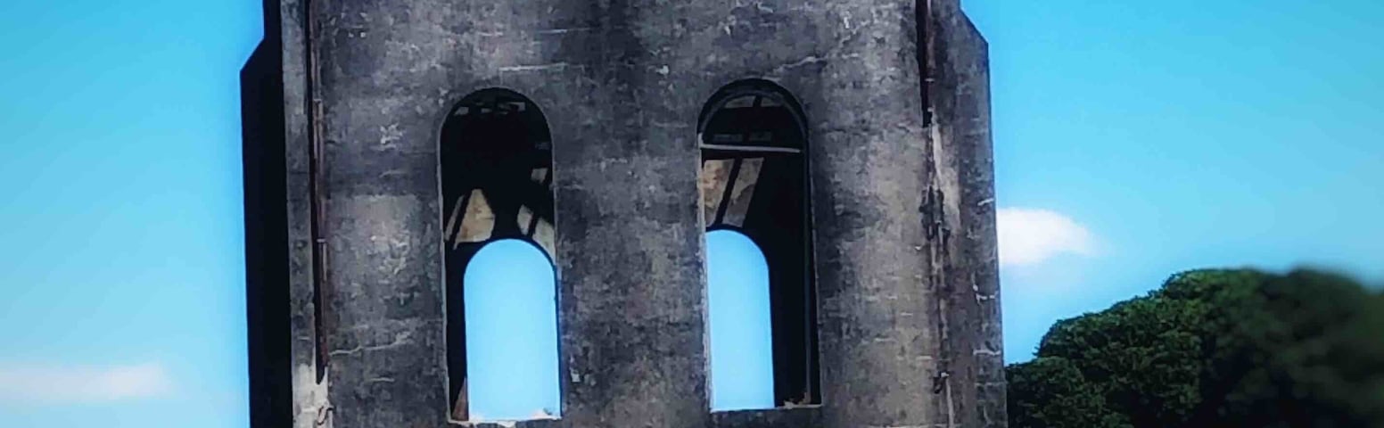 Um antigo campanário de pedra com janelas em arco e um relógio.