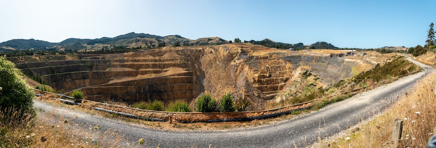 Uma área de mineração com terraços de escavação, uma linha férrea e uma estrada serpenteando pela paisagem.