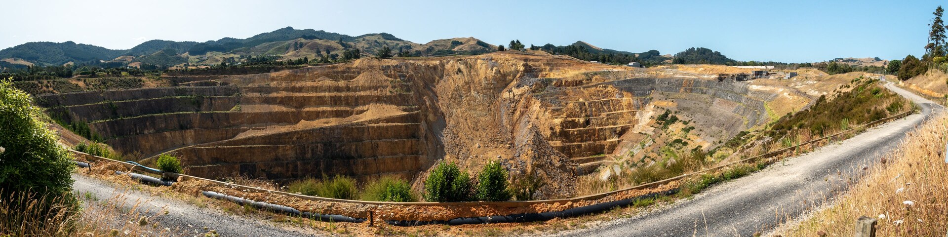 Uma área de mineração com terraços de escavação, uma linha férrea e uma estrada serpenteando pela paisagem.