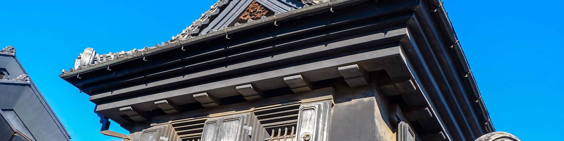 Um edifício japonês tradicional com telhas ornamentadas e um pináculo decorativo.
