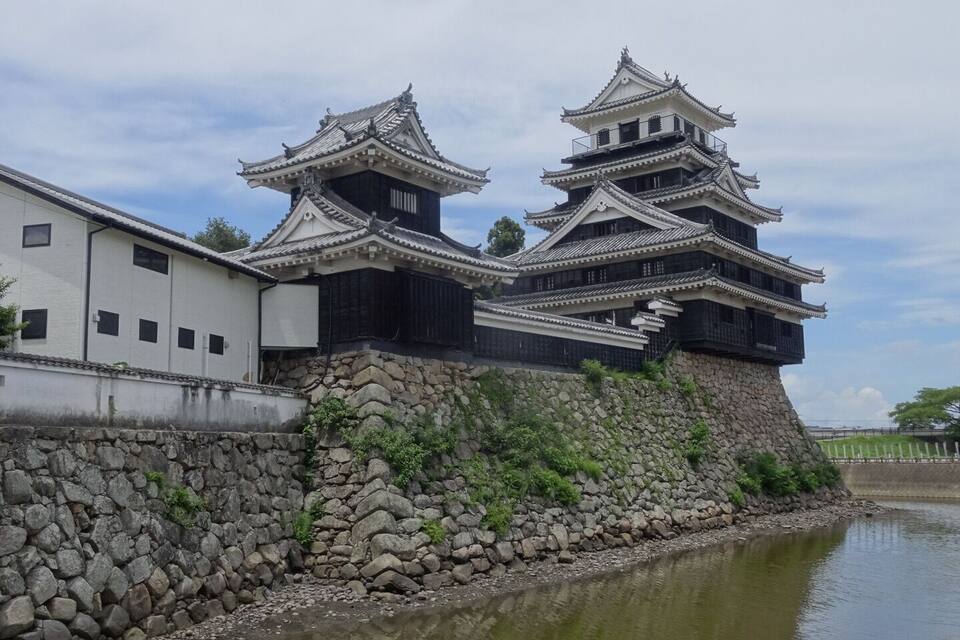 Um castelo japonês tradicional, com vários níveis e uma parede de pedra.