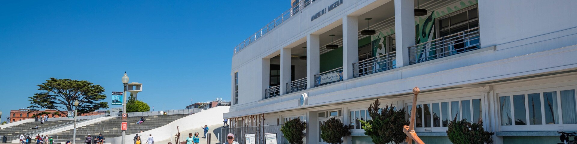 Um calçadão à beira-mar com um Museu Marítimo, uma grande escultura de navio e uma escadaria que leva a uma plataforma de observação.
