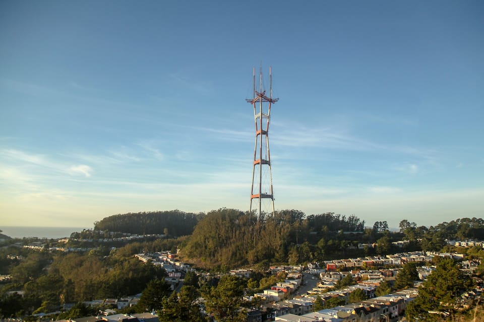 Uma torre de telecomunicações numa área residencial com casas e árvores.