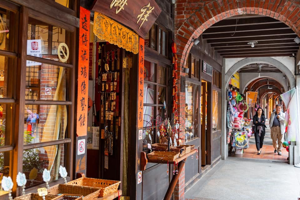 Uma viela estreita com lojas tradicionais, arquitetura em tijolo e decorações penduradas.