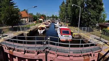 Um canal com barcos, uma ponte para pedestres e casas ao longo da água.