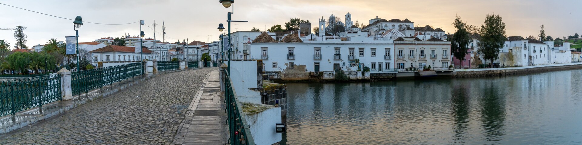 Um calçadão à beira-mar com edifícios históricos e uma grade de metal verde.