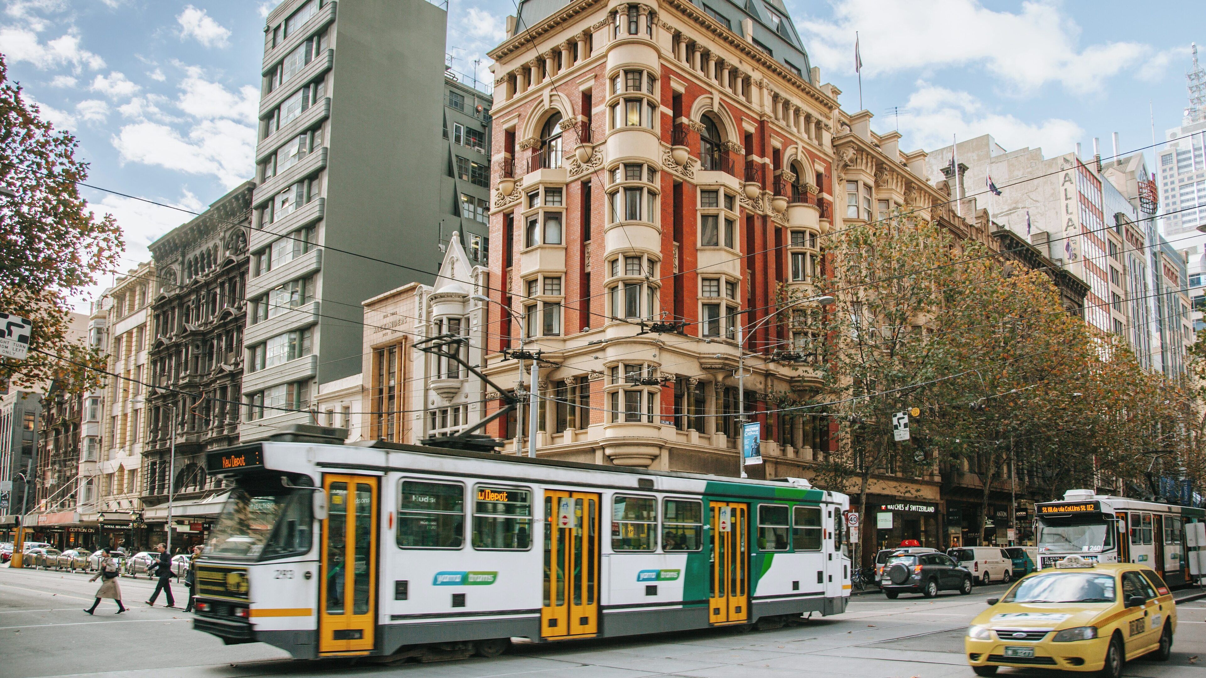 Collins Street bustling with trams and taxis in Docklands, Melbourne, showcasing vibrant city life and historic architecture during the day