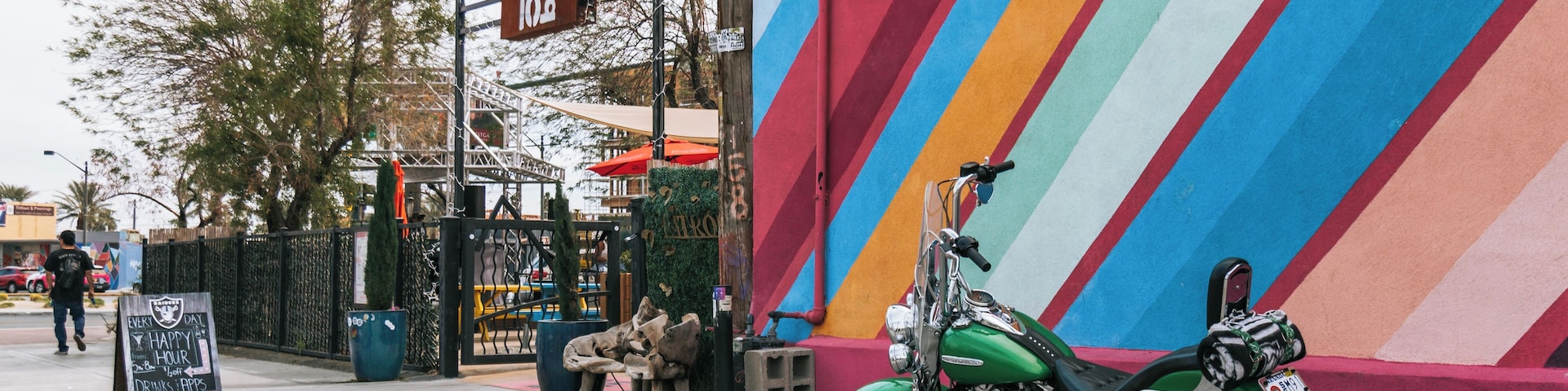 Uma motocicleta verde estacionada em frente a um mural colorido.