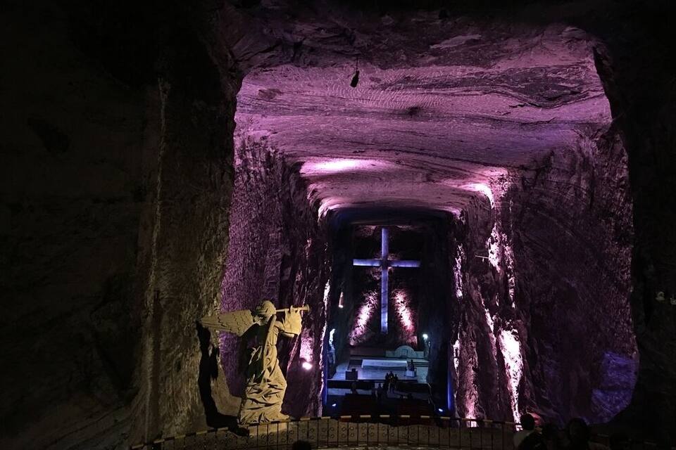 Caverna com uma cruz no final, iluminada por iluminação roxa.