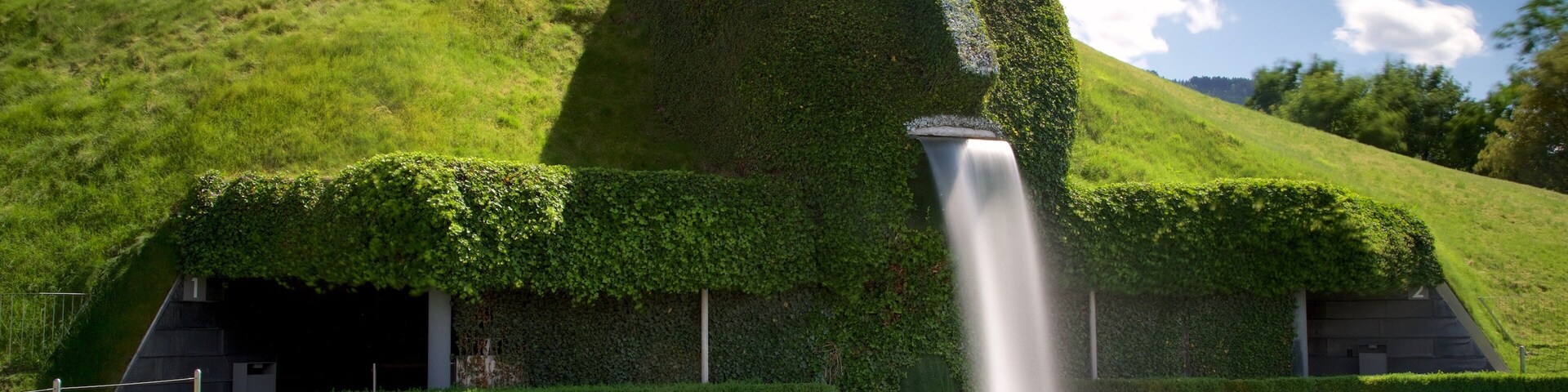 Uma colina com uma estrutura semelhante a rosto, uma cascata e uma piscina.